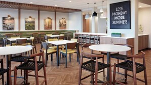 Um restaurante com mesas redondas, cadeiras e obras de arte nas paredes.