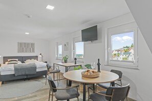 Quarto moderno com cama, mesa de cabeceira e televisão.