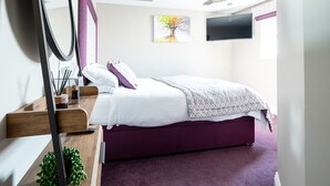 Quarto moderno com uma cama, uma televisão e um quadro na parede.
