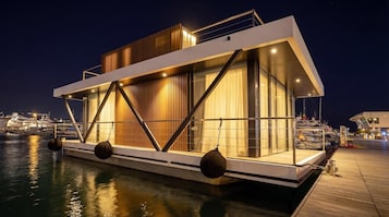 Uma estrutura moderna flutuante com deck, janelas amplas e fachada de madeira.
