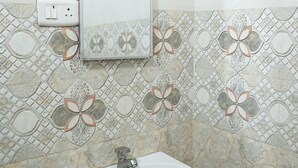 Casa de banho com lavatório branco, espelho e azulejos estampados na parede.