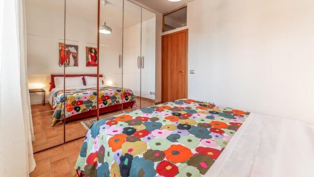 Quarto com cama, guarda-roupa, espelho e porta.