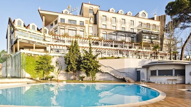 Um hotel com vários andares, piscina, área de estar externa e escadaria que dá acesso aos níveis superiores.