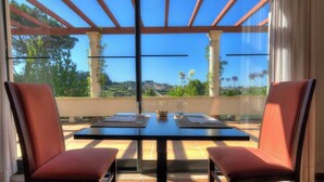 Um terraço com mesa e cadeiras, uma pérgula e vista para a paisagem.