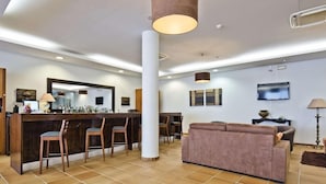 Uma sala de estar ampla com bar, assentos e televisão.