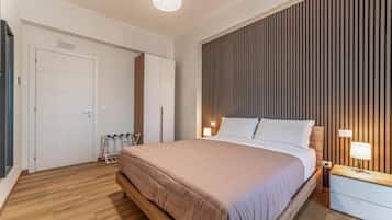 Quarto moderno com uma cama grande, cabeceira de ripas de madeira, mesa de cabeceira com abajur e um guarda-roupa.