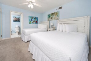 Quarto com duas camas, um ventilador de teto e obras de arte nas paredes.