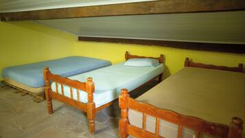 Quarto com duas camas de madeira, parede amarela e teto inclinado.