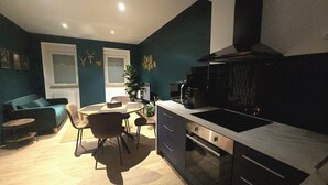 Cozinha compacta com área de refeições, sofá e máquina de café.
