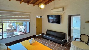 Quarto de hotel com uma cama, um sofá, uma televisão e uma pequena mesa.