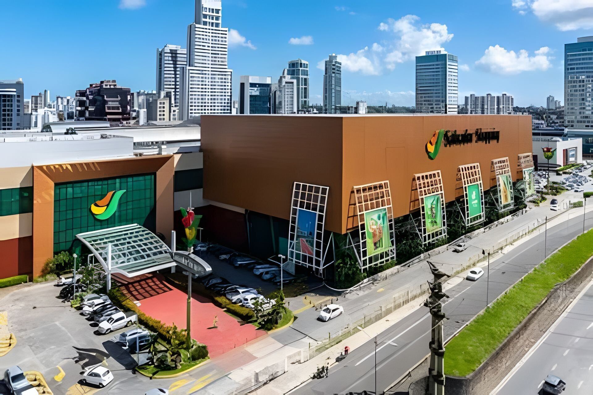 Um edifício moderno com um logotipo em destaque, um estacionamento e o horizonte da cidade ao fundo.