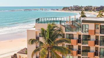 Um hotel na praia com piscina, varandas e vista para a praia e o oceano.