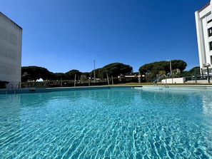 Piscina cristalina com vista para edifícios e árvores ao redor.