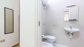 Uma casa de banho com sanita, bidé e lavatório.