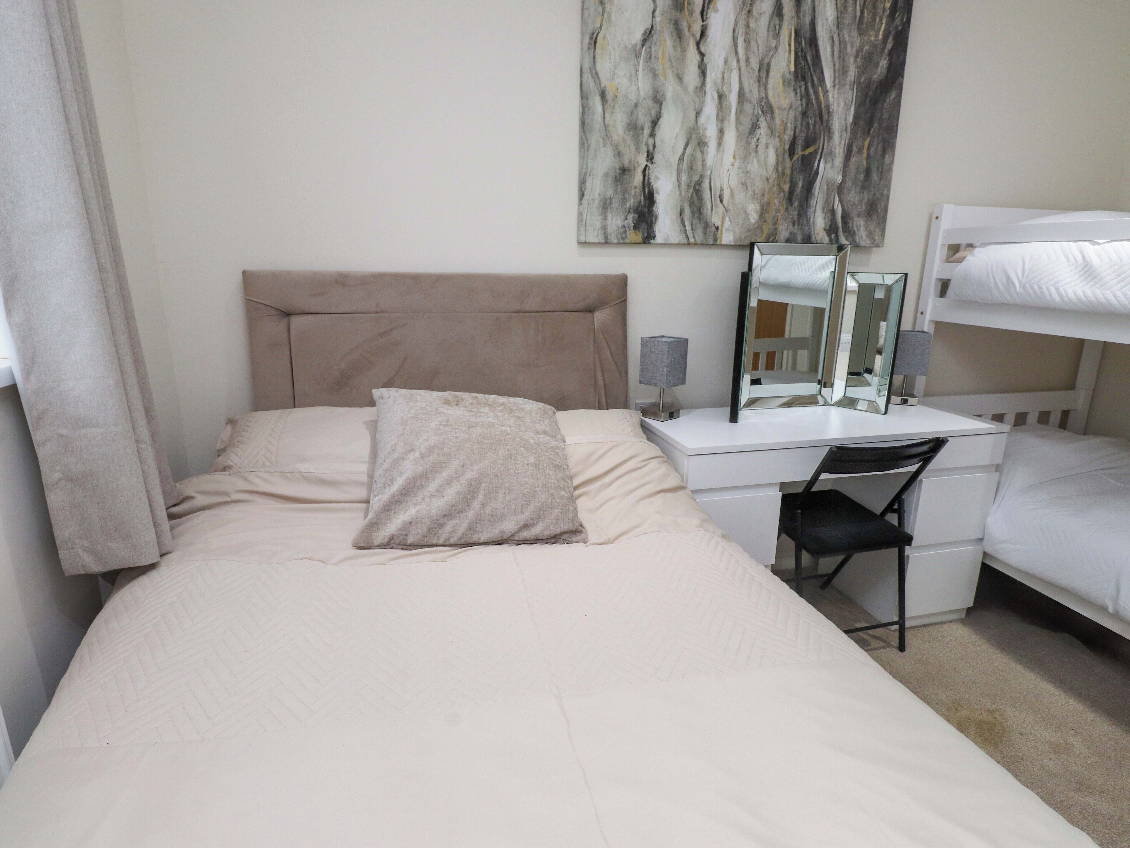 Quarto com cama, escrivaninha, cadeira, espelho e beliche.