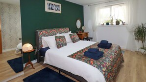 Quarto com cama, cômoda, espelho, janela com cortinas e planta em vaso.