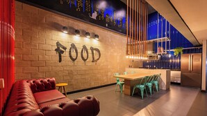 Um interior moderno com um sofá vermelho, uma área de jantar com cadeiras verdes e uma cozinha com geladeira de aço inoxidável.