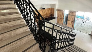 Uma escadaria com guarda-corpo de metal preto, assoalho de madeira e luminárias pendentes.