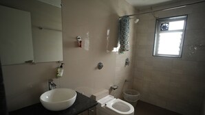 Casa de banho com lavatório, sanita e chuveiro.