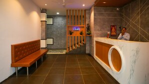 Uma área de recepção com um banco de madeira, um balcão de atendimento com design circular e uma escada com corrimão de madeira.