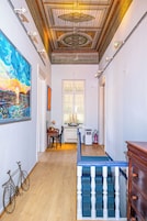 Um corredor com escadas, uma área de refeições e um quadro na parede.