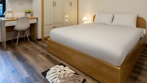 Quarto com cama, escrivaninha, cadeira, guarda-roupa e um quadro na parede.