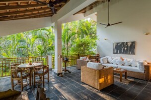 Um espaço ao ar livre coberto com uma mesa de jantar, cadeiras, um sofá e um ventilador de teto.