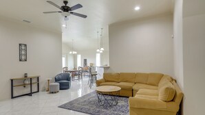 Uma sala de estar com sofá, mesa de centro redonda e ventilador de teto.
