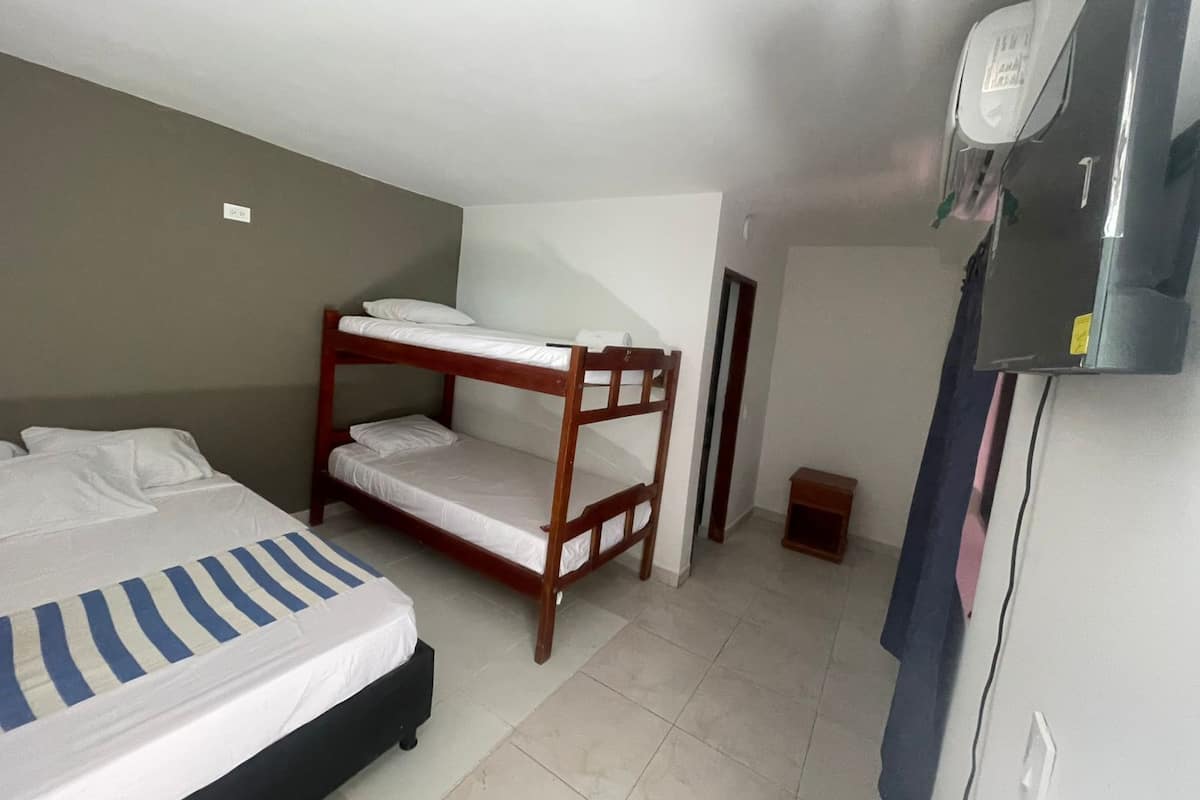 Quarto com beliches, um pequeno armário e uma porta que dá para outro cômodo.