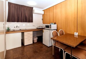Cozinha compacta equipada com micro-ondas, mini refrigerador, pia e área de refeições com mesa e cadeiras.