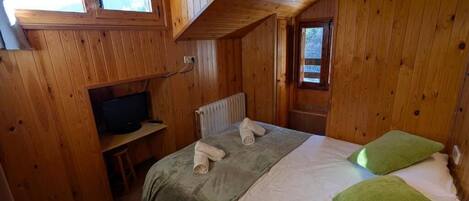 Quarto de madeira com uma cama, televisão e janela.