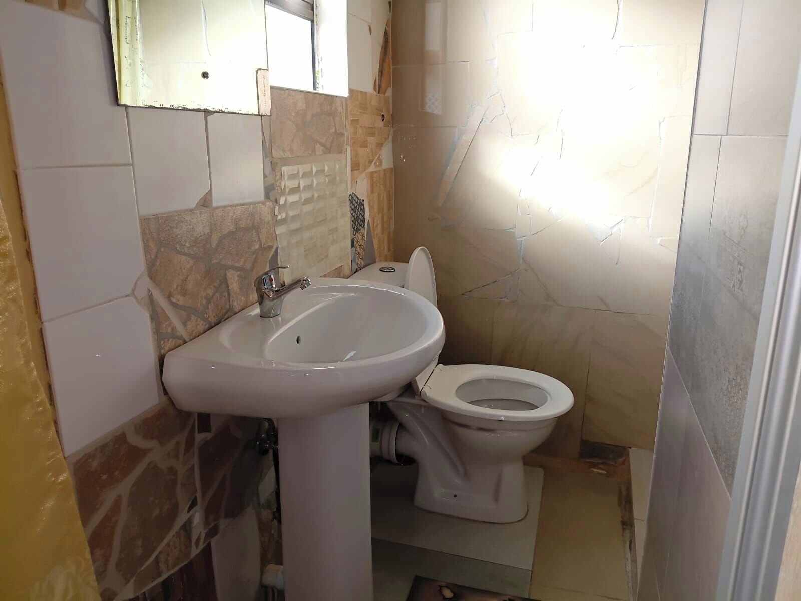 Casa de banho com lavatório, sanita e espelho.