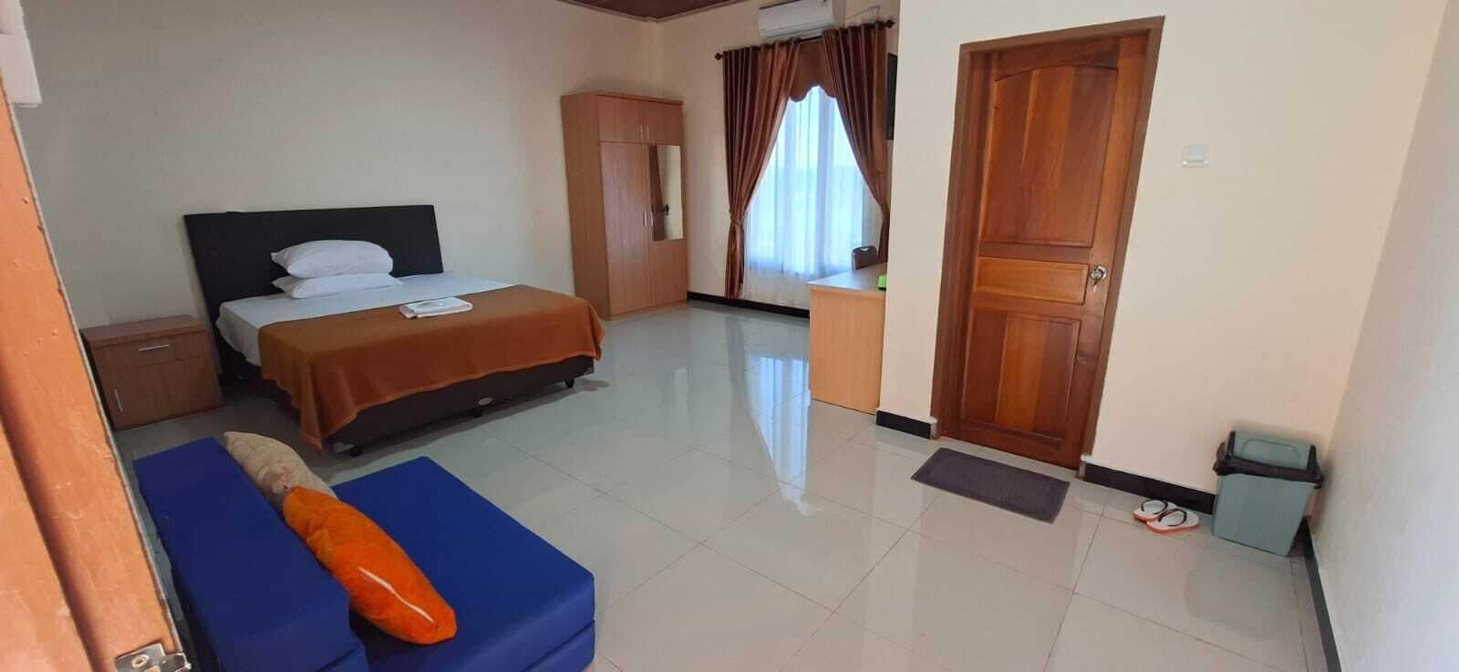 Quarto de hotel com cama, escrivaninha, armário e banheiro.