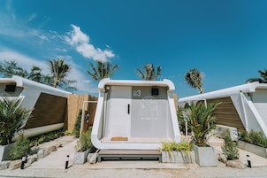 Um edifício moderno com um design arquitetônico único, apresentando uma entrada imponente com porta de ripas de madeira e uma placa com a inscrição 'SeaSand Seesky'.