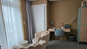 Quarto com escrivaninha, duas cadeiras, abajur e um vaso decorativo.
