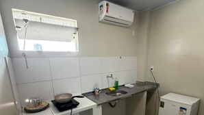 Uma pequena cozinha compacta com fogão, pia e geladeira.