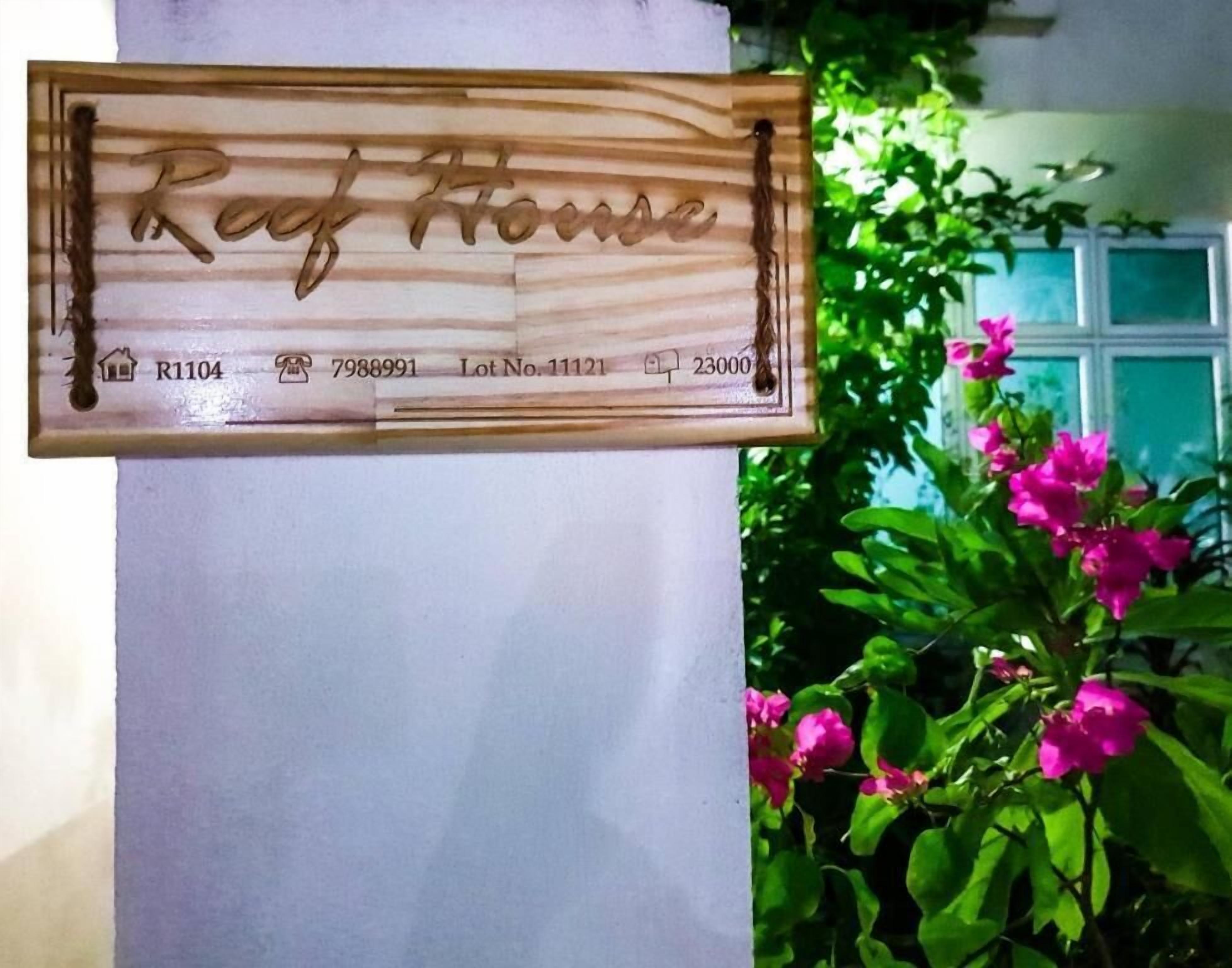 Uma placa de madeira com 'Red House' e informações de contato.