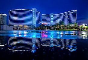 Um hotel com vários andares e design circular, com um pátio central e reflexo na água.