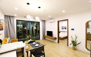 Quarto de hotel moderno com área de refeições, TV, cama e aparelho de ar condicionado.