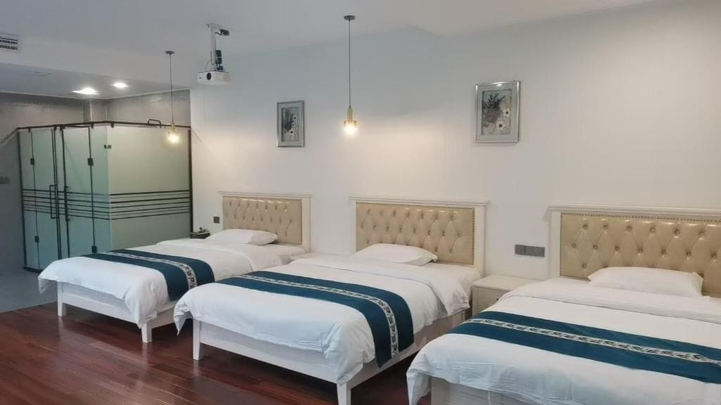 Quarto de hotel com três camas, um guarda-roupa e um espelho.
