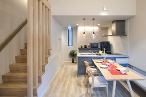 Cozinha moderna com ilha central, escada de madeira e iluminação pendente.