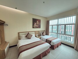 Quarto de hotel com duas camas, um quadro na parede e uma janela grande com vista para edifícios.