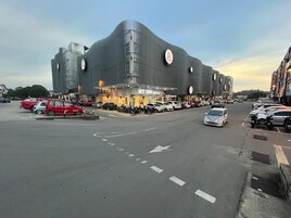 Um hotel moderno com fachada curva singular, um estacionamento com carros e céu claro.