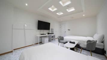 Um quarto moderno com cama, escrivaninha, cadeira, televisão e teto com claraboias.