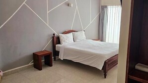 Um quarto com uma cama, mesa de cabeceira e guarda-roupa.