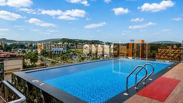 Piscina no terraço com vista para a paisagem urbana e montanhas.