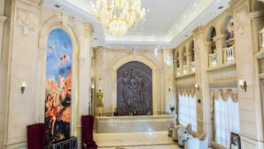 Um amplo hall com um grande candelabro, piso de mármore e arquitetura clássica.