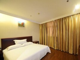 Quarto de hotel com uma cama, mesa de cabeceira, um quadro na parede e cortina.
