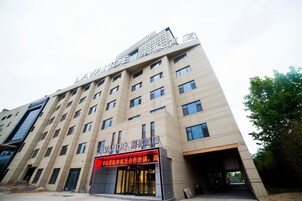 Um hotel com vários andares e uma placa grande na entrada.