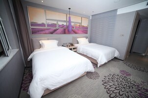 Quarto de hotel com duas camas, uma janela grande com vista para campos de lavanda, uma luminária pendente moderna e um tapete estampado.